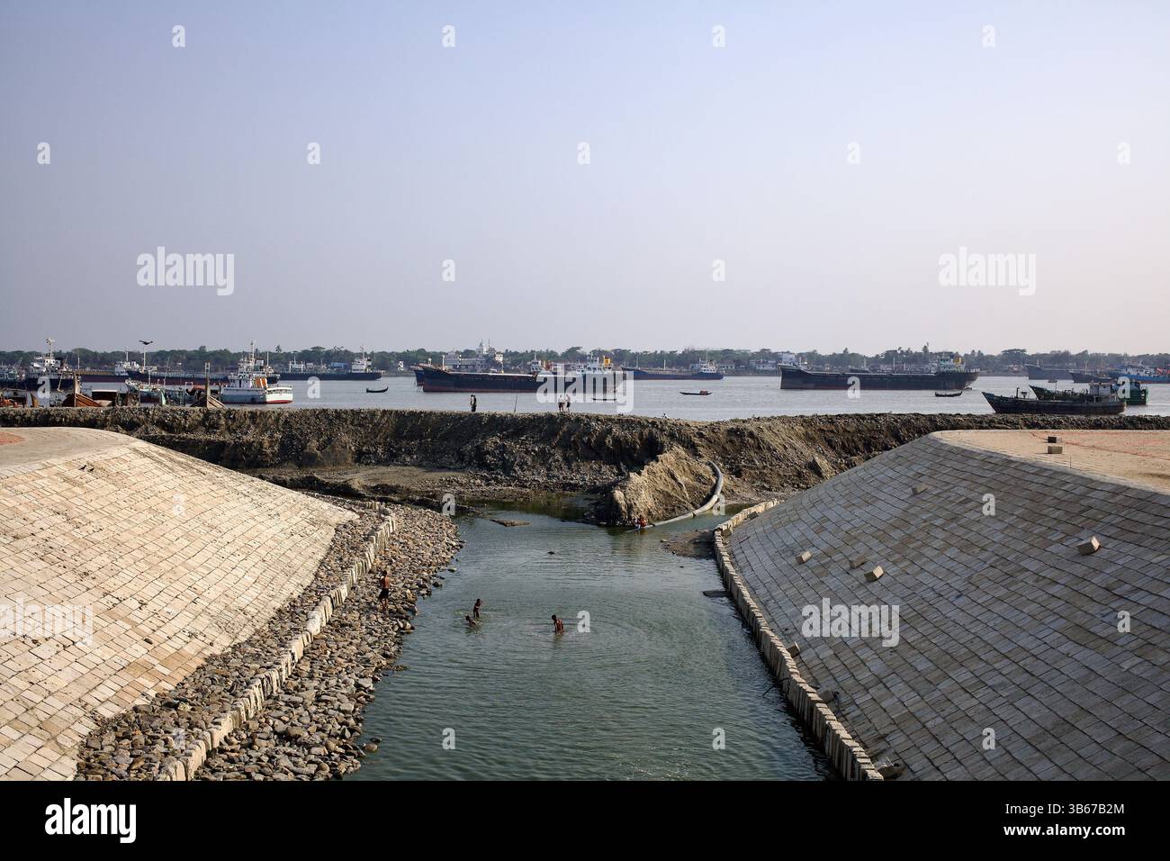 Cargo ships navigate the Karnaphuli River as construction progresses on ...