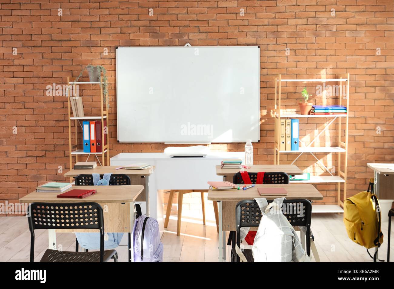 Interior of empty classroom with whiteboard, desks and shelf units ...
