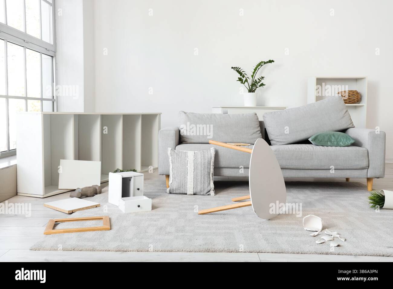 Interior of messy living room with sofa, overturned table and shelf ...