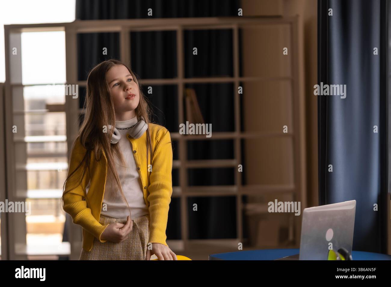 Thoughtful schoolgirl in yellow cardigan dreaming about future learning ...