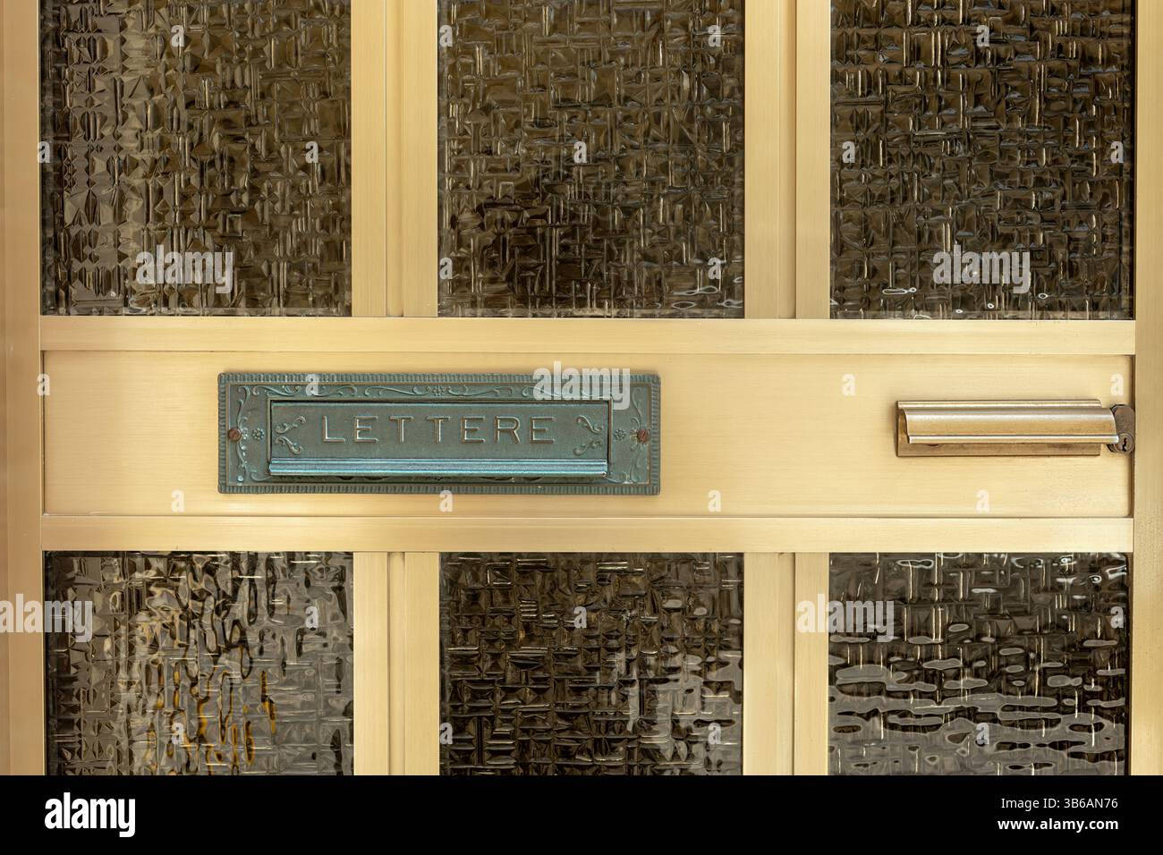 Close-up of a scratched golden metal door with textured glass, an ...