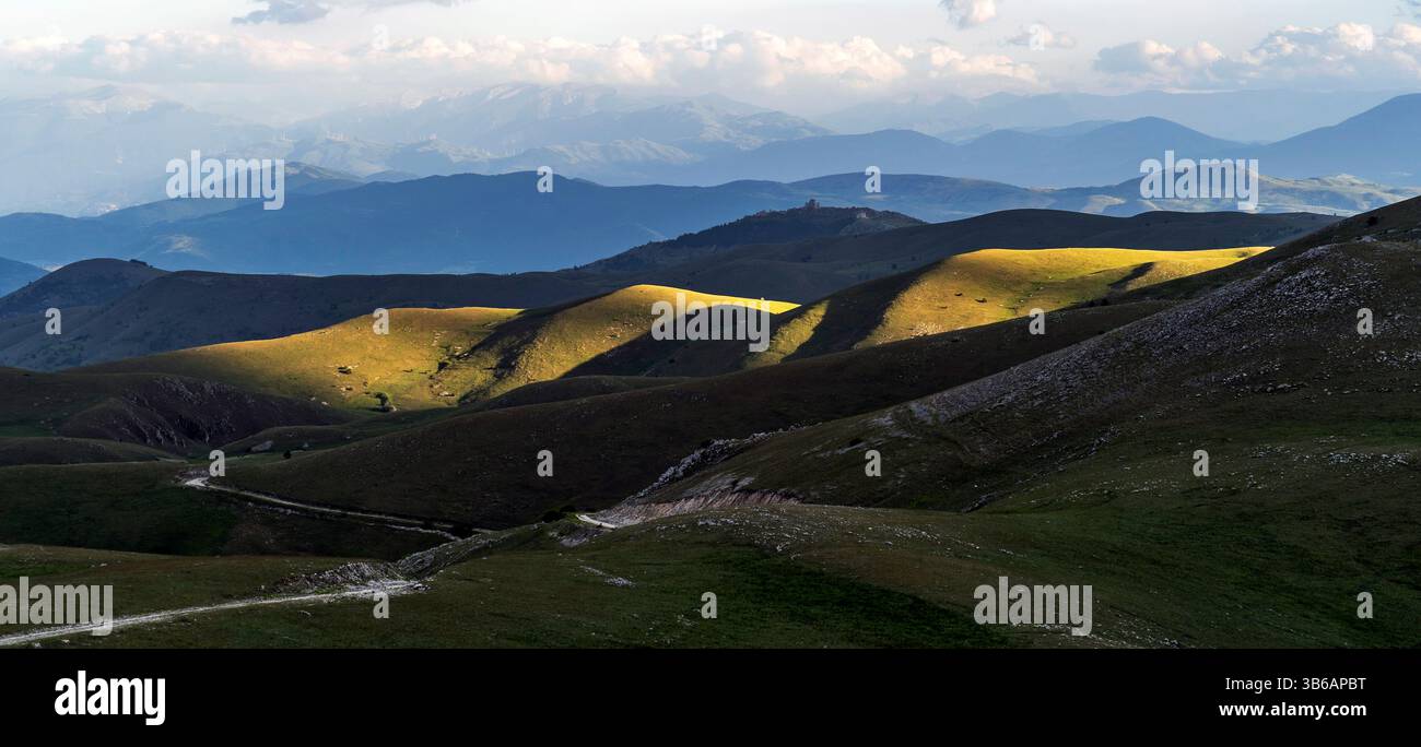 A panoramic view of rolling hills and mountains under a cloudy sky. The ...