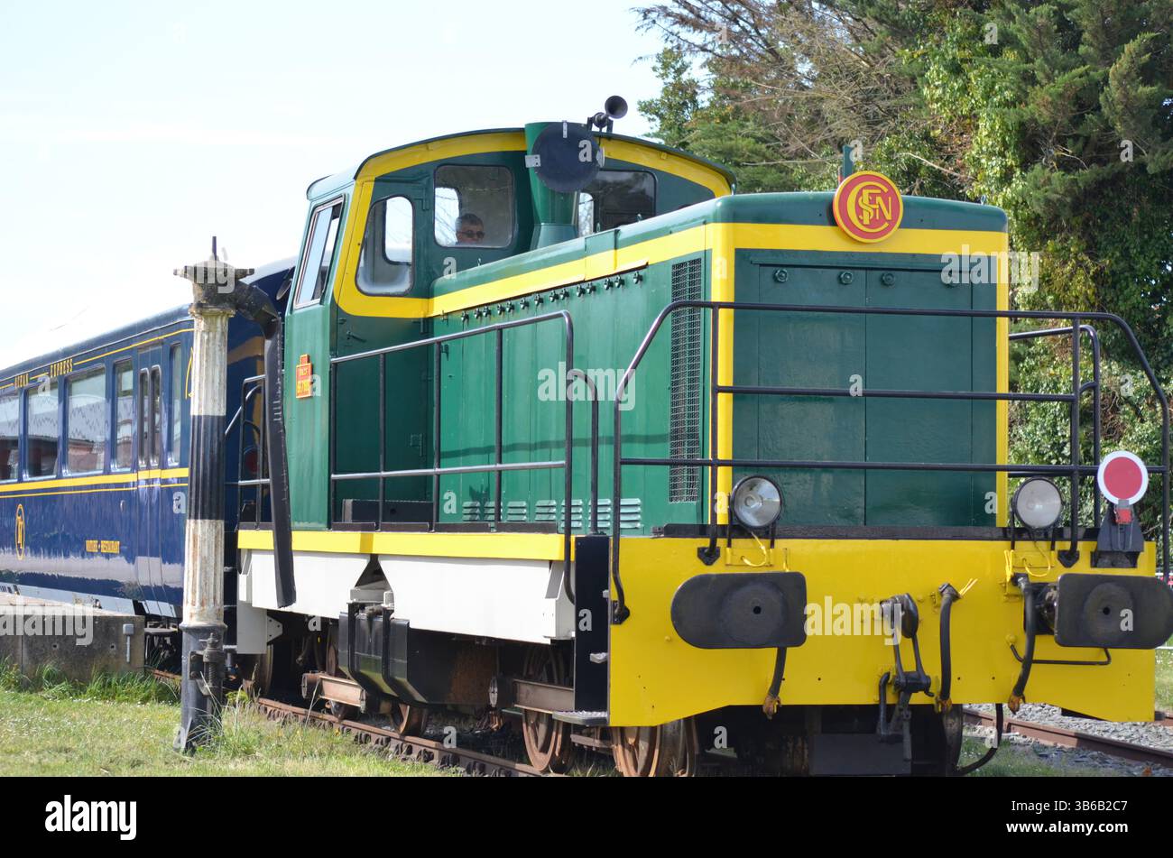 Vintage green and yellow diesel locomotive parked beside a classic blue ...