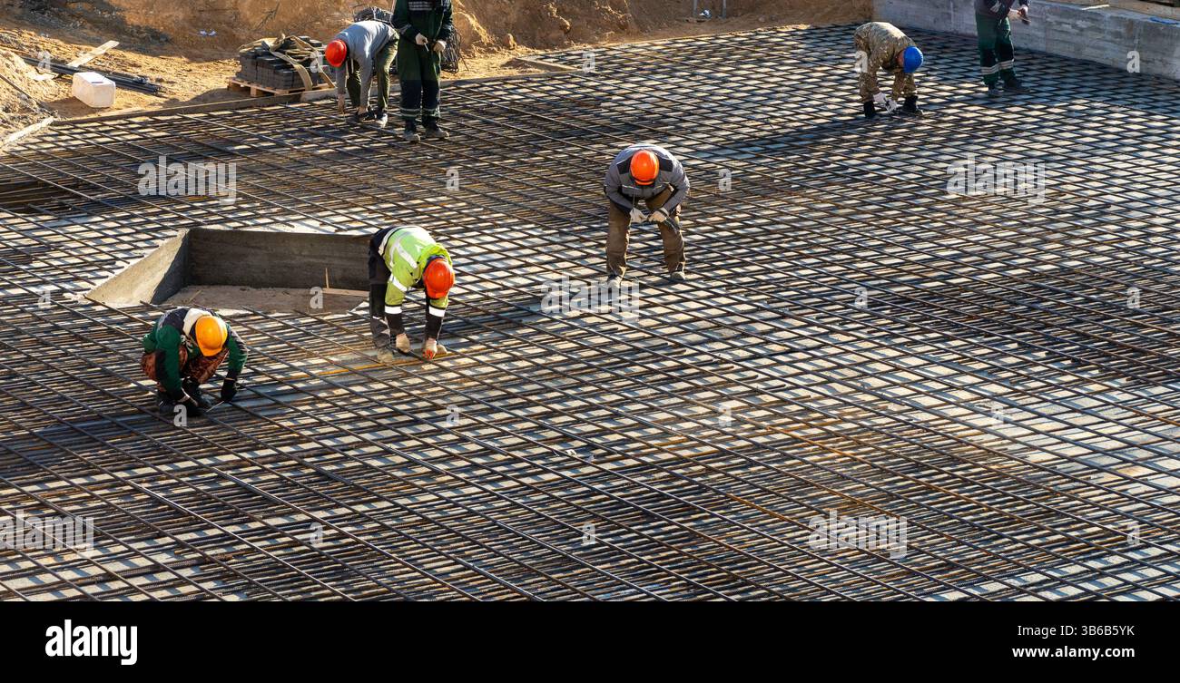 Brigade of builders knit fittings for pouring concrete. Workers ...