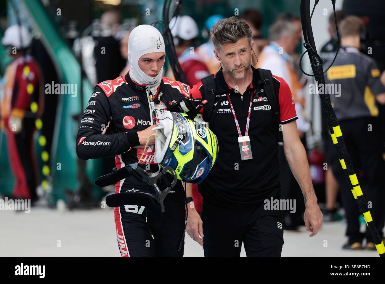 Haas driver Oliver Bearman of Britain, left, walks through the pit area ...
