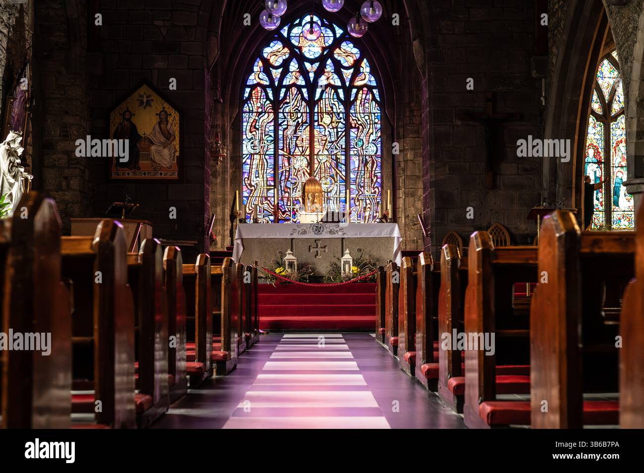 View down the aisle of a historic Irish church with wooden pews, ornate ...