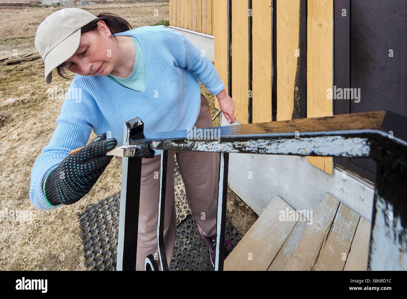 Coating metal porch railing with anticorrosive paint, homeowner ensures ...
