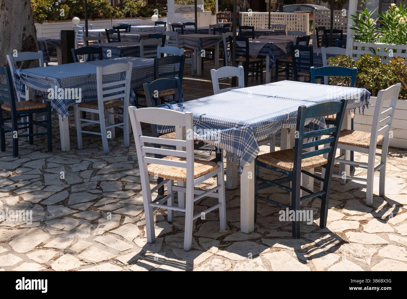 Traditional outdoor Greek taverna setup with blue checkered tablecloths ...