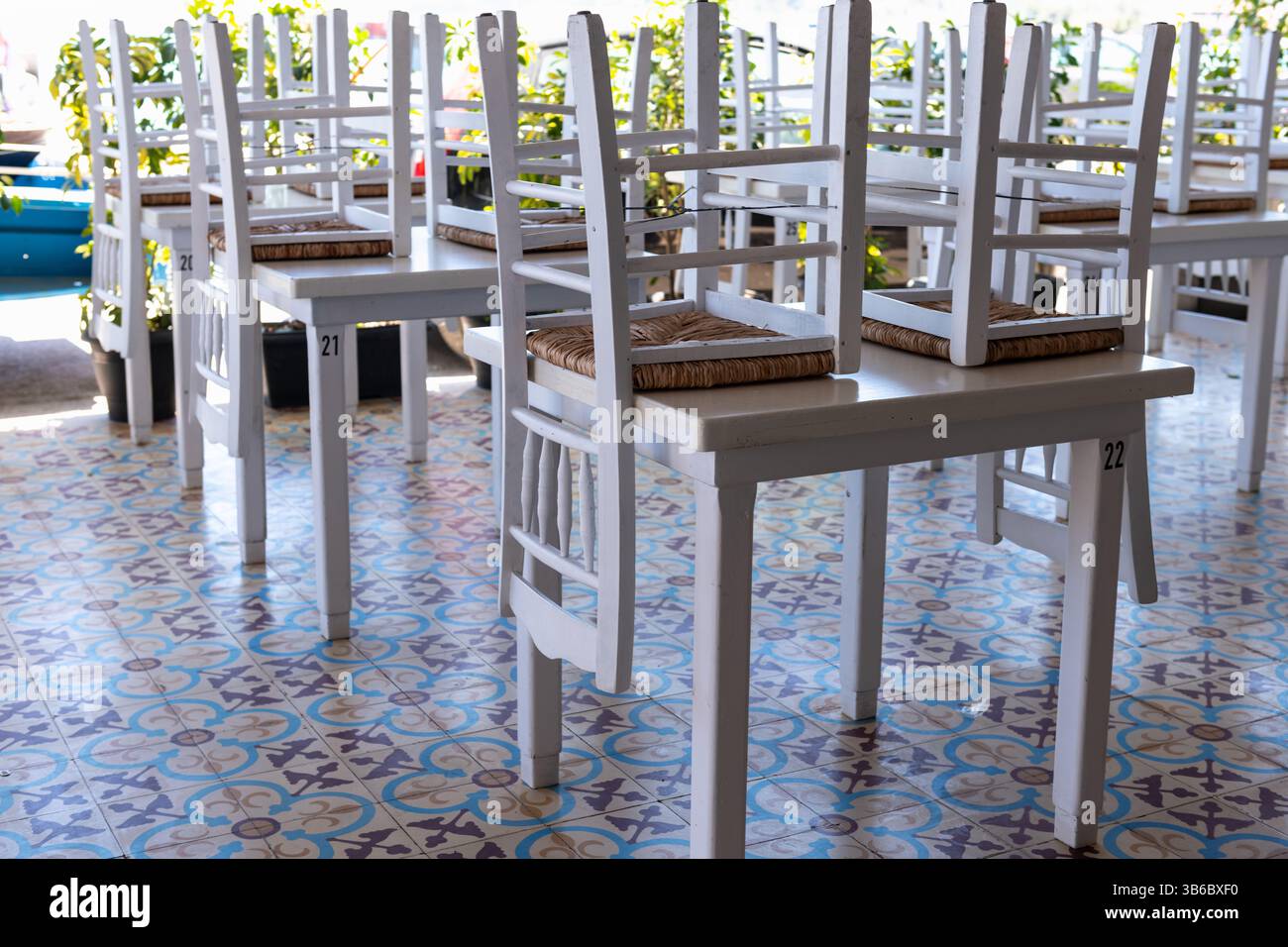 White wooden chairs stacked on tables in a closed Greek island ...