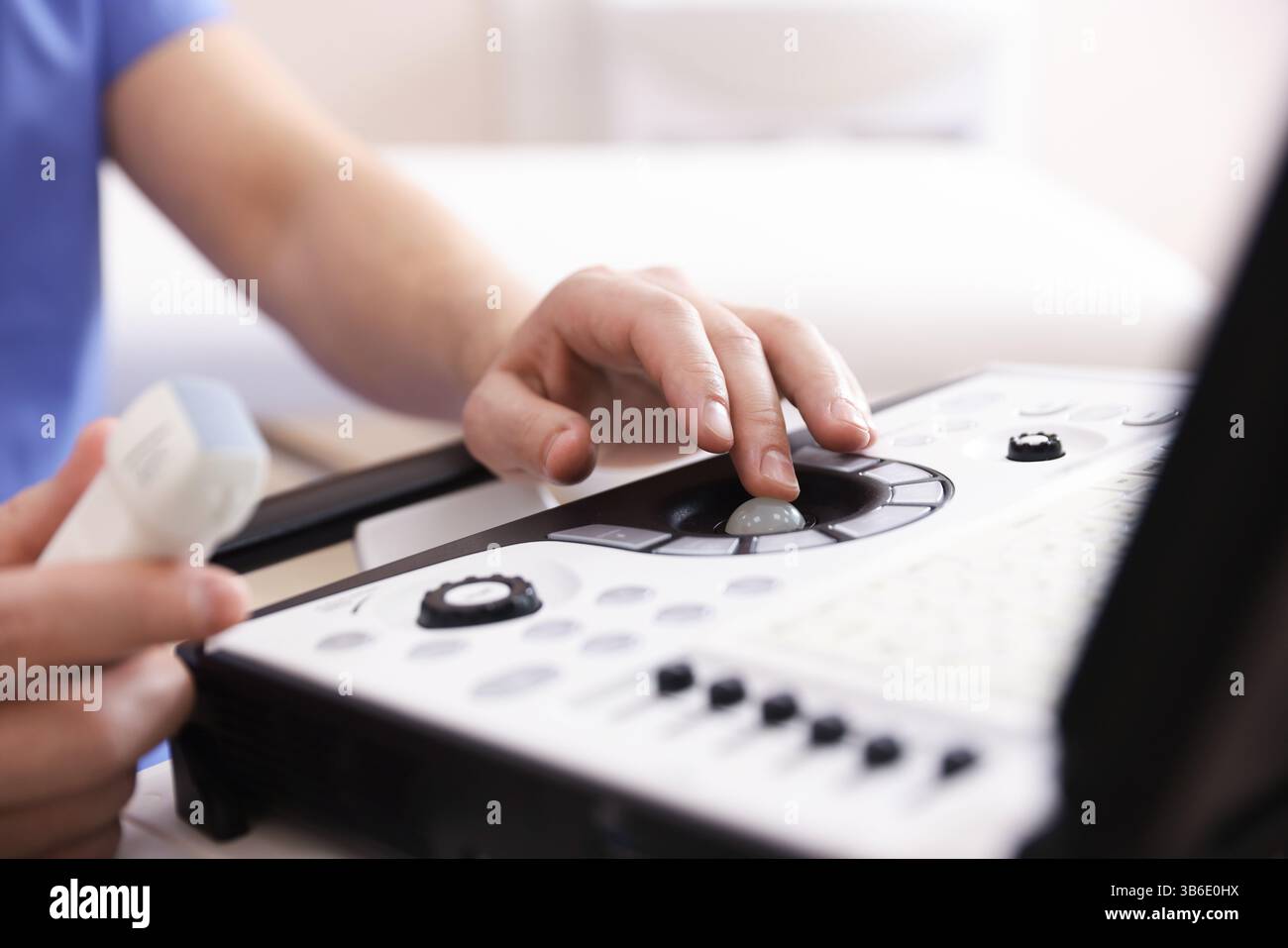 Sonographer with transducer and ultrasound machine in clinic, closeup ...