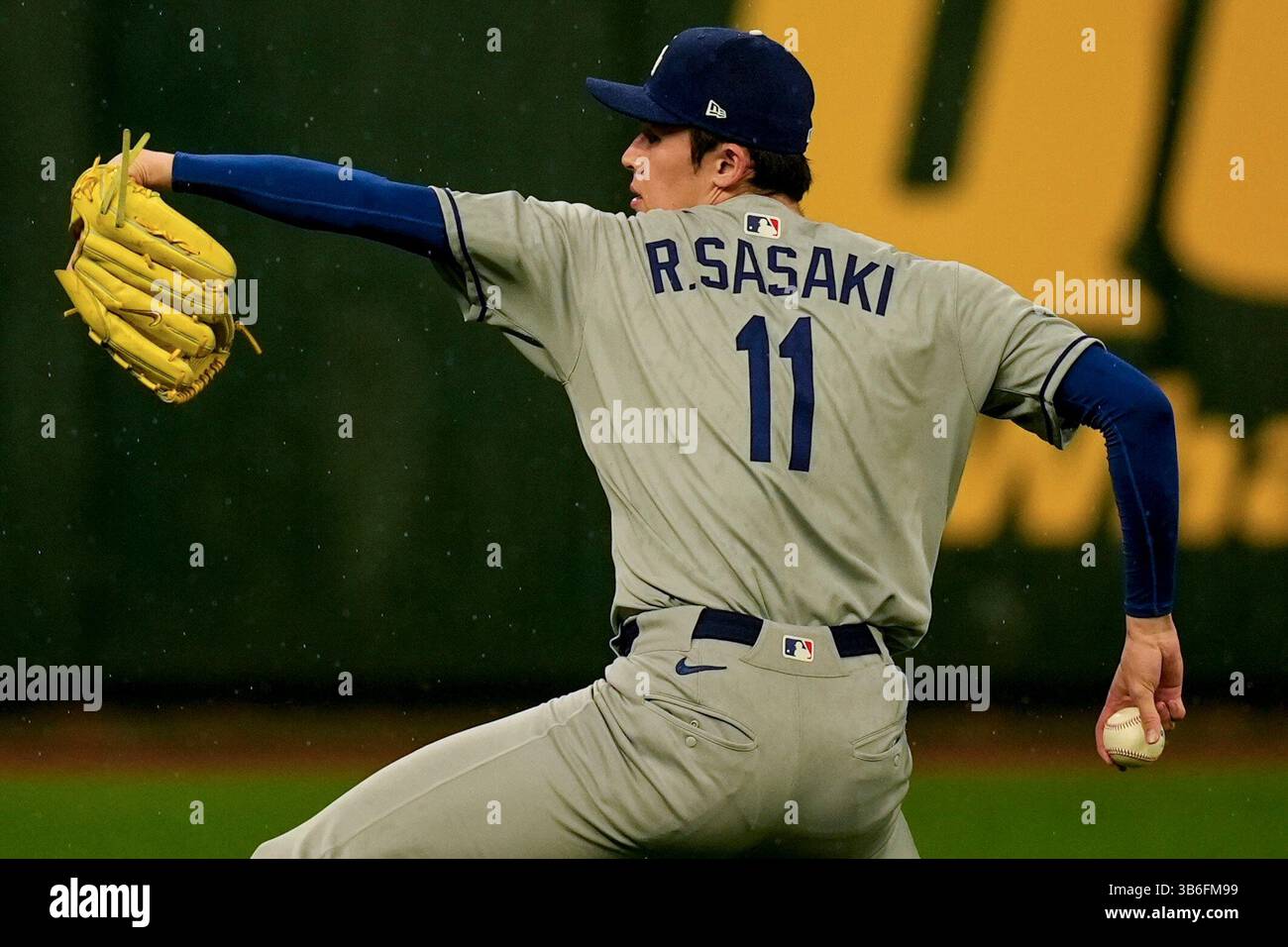 Los Angeles Dodgers pitcher Roki Sasaki warms up in the rain ahead of a ...