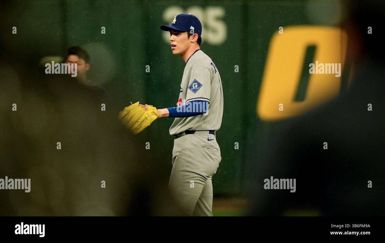 Los Angeles Dodgers pitcher Roki Sasaki warms up in the rain as ground ...