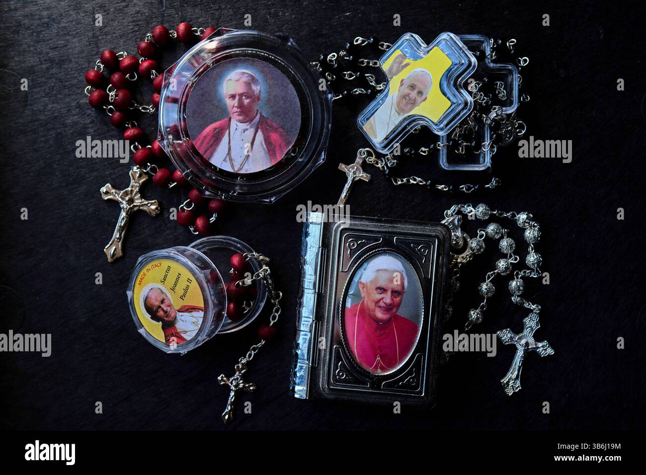 From top left and clockwise: boxes of rosaries with pictures of Pope ...