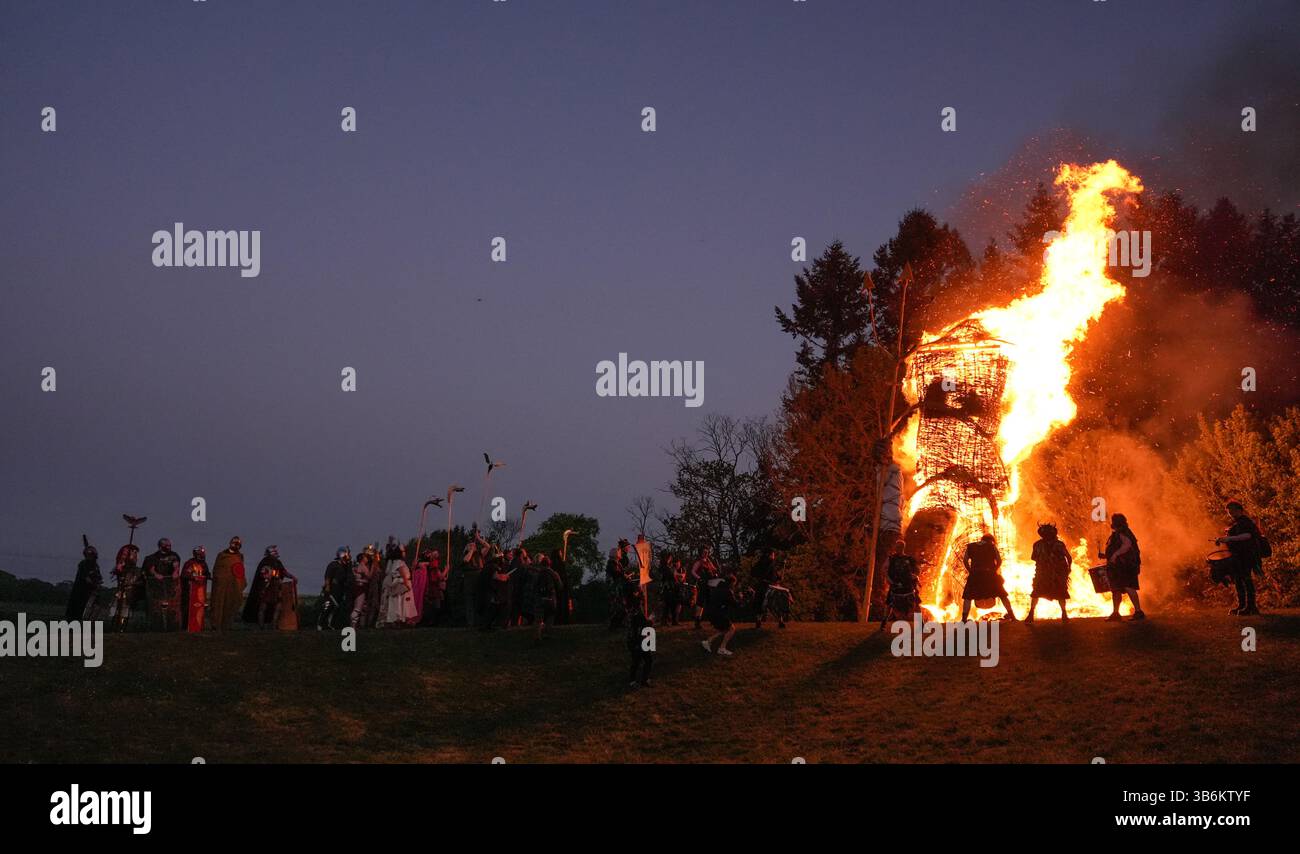 Members of the Pentacle Drummers perform in front of a burning wicker ...