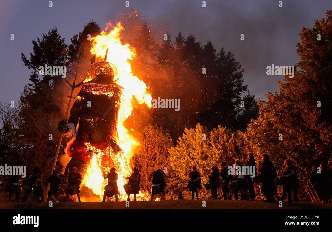 Members of the Pentacle Drummers perform in front of a burning wicker ...