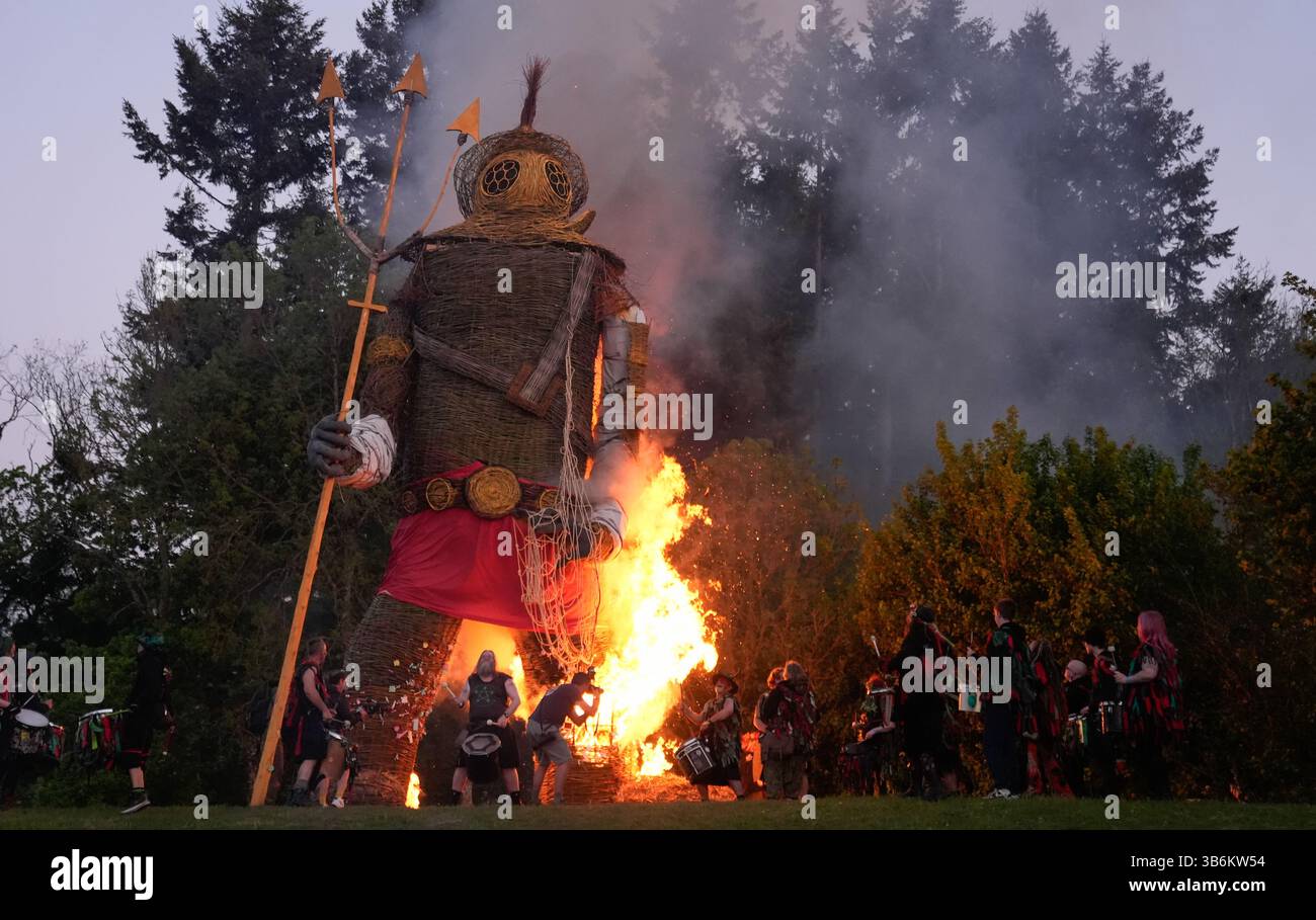 Members of the Pentacle Drummers perform in front of a burning wicker ...