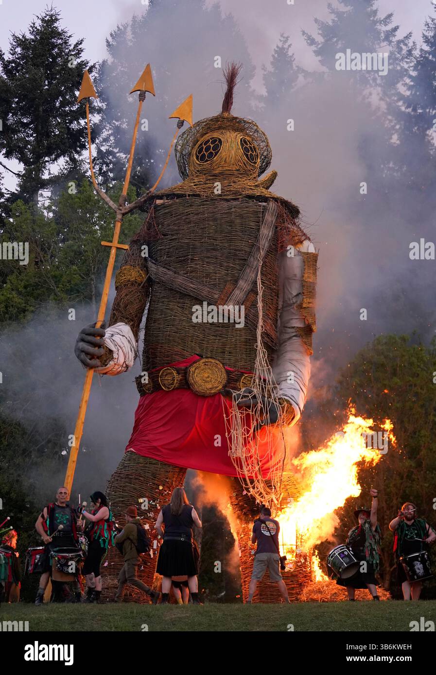 Members of the Pentacle Drummers perform in front of a burning wicker ...