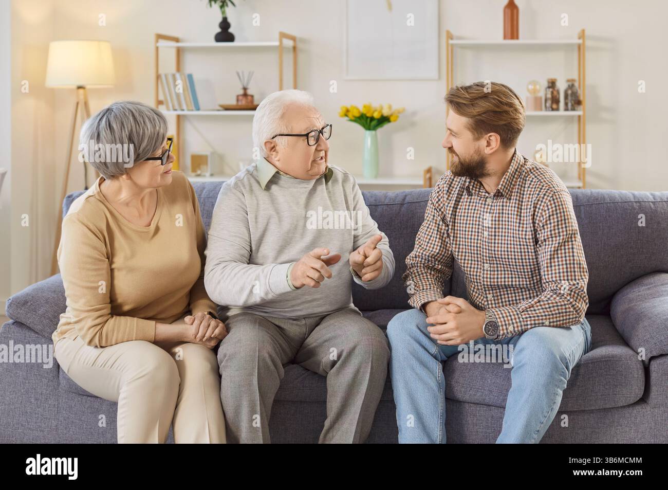Family of senior old parents and adult son sitting on sofa at home and ...