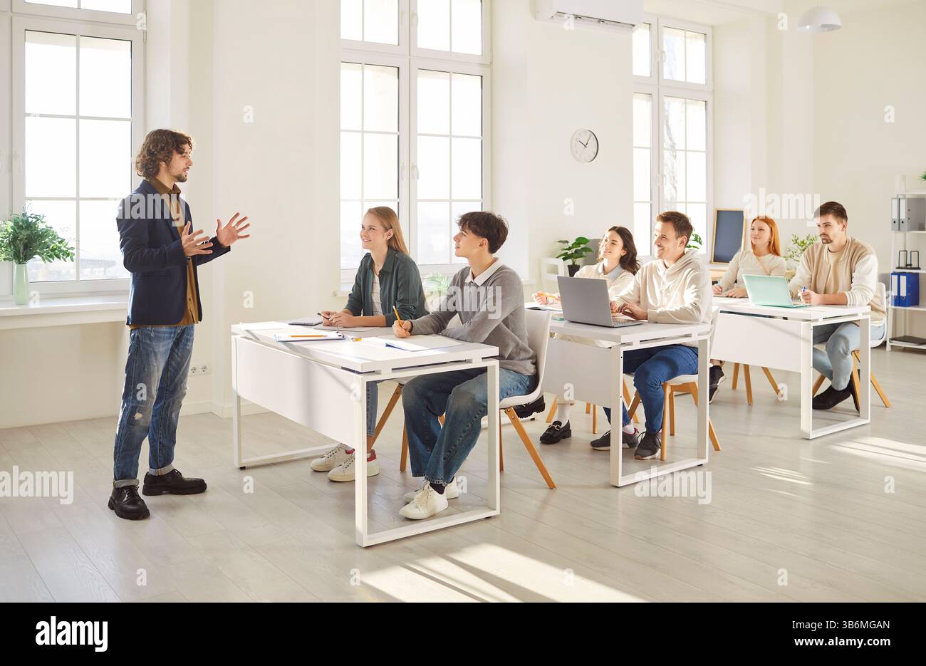 Male teacher conducting lesson in classroom while university students ...