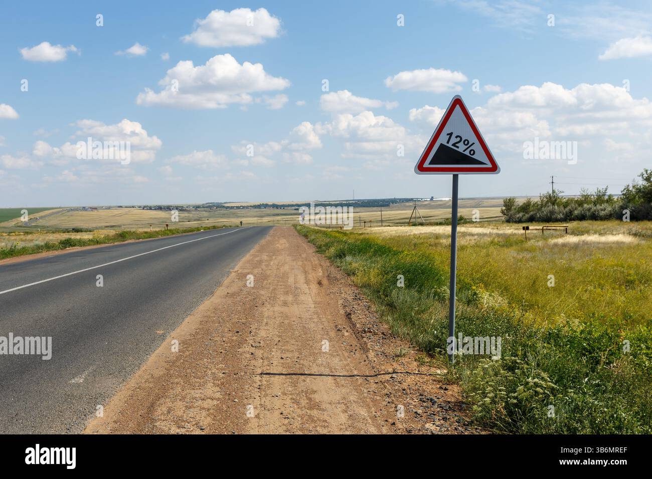 A steep gradient road sign is positioned beside a rural highway ...