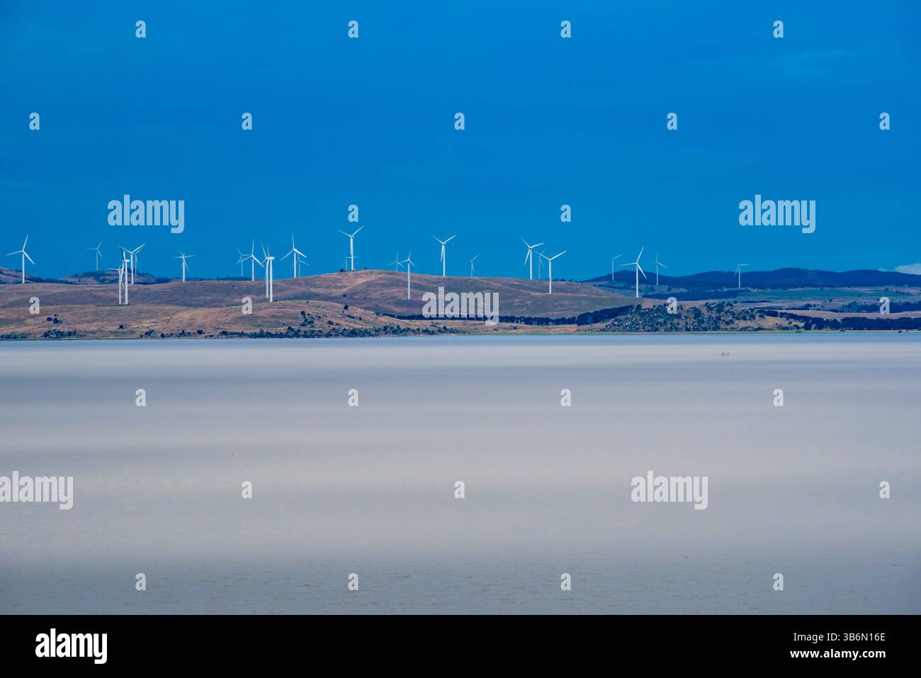 Blue grey skies and a milky grey Lake George are intersected by green ...