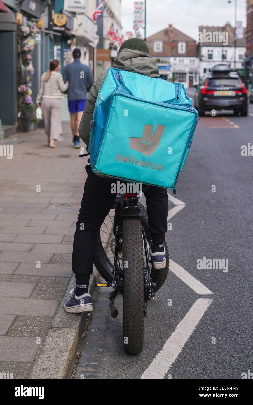 London UK 4 May 2025. A Deliveroo rider making deliveries on Wimbledon ...