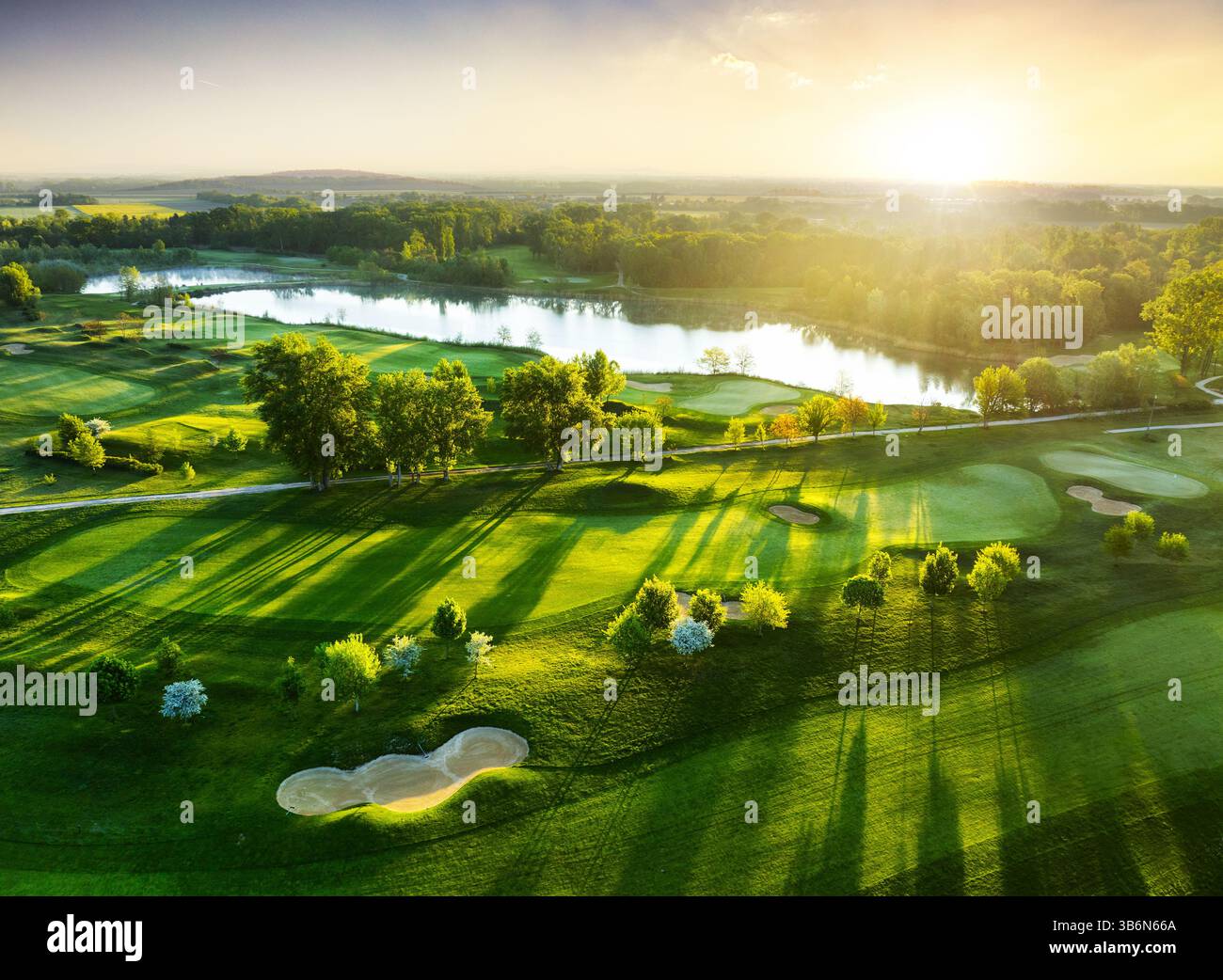 Aerial view of sunset over golf course with spring colored trees and ...