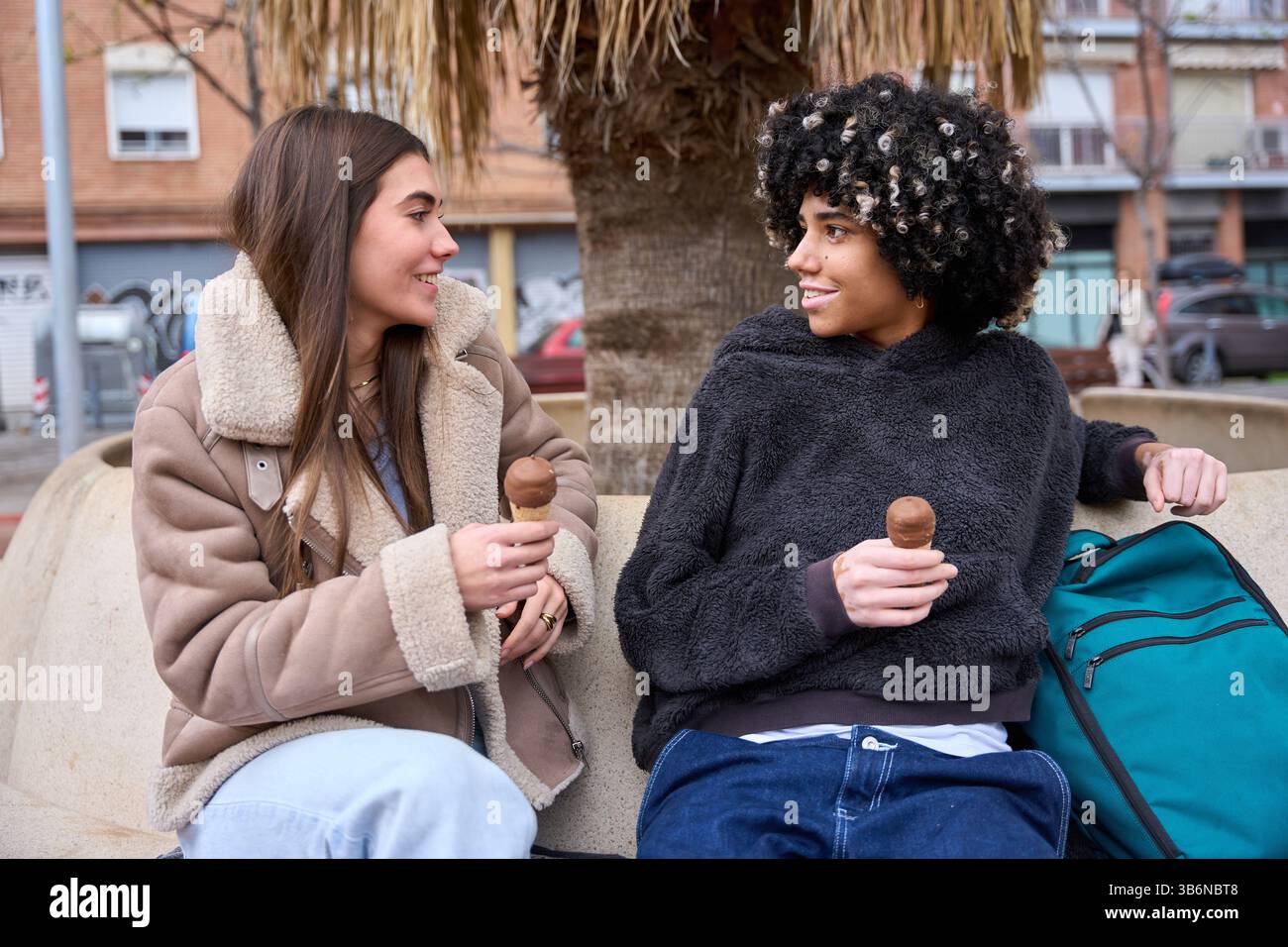 Female students enjoying ice cream together on a bench Stock Photo - Alamy