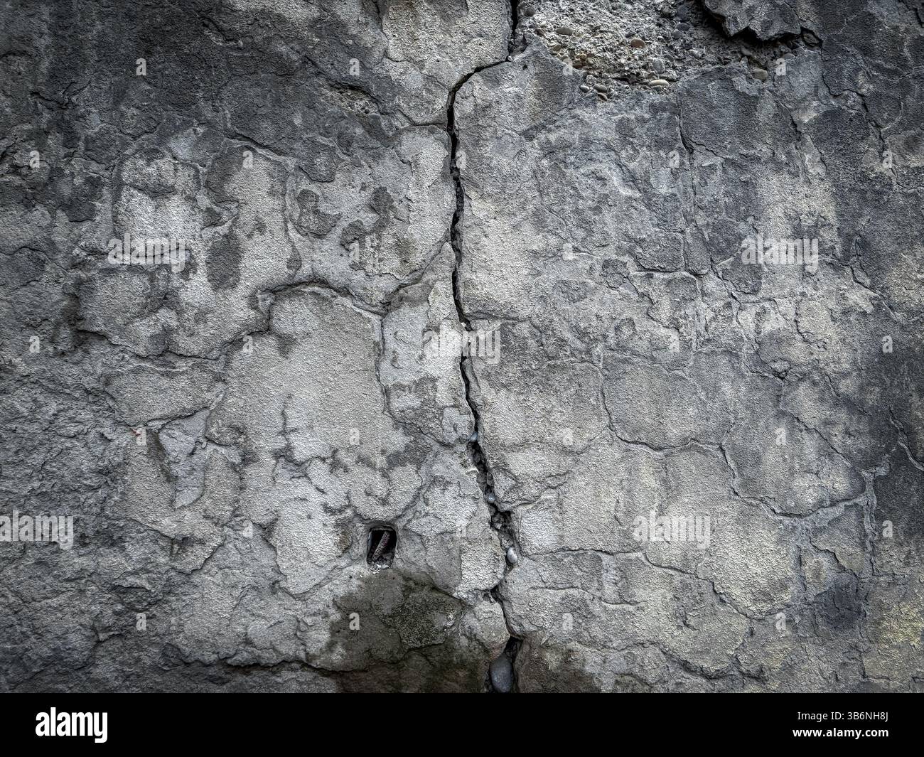 Close-up of cracked concrete wall with deep fracture line, rough ...