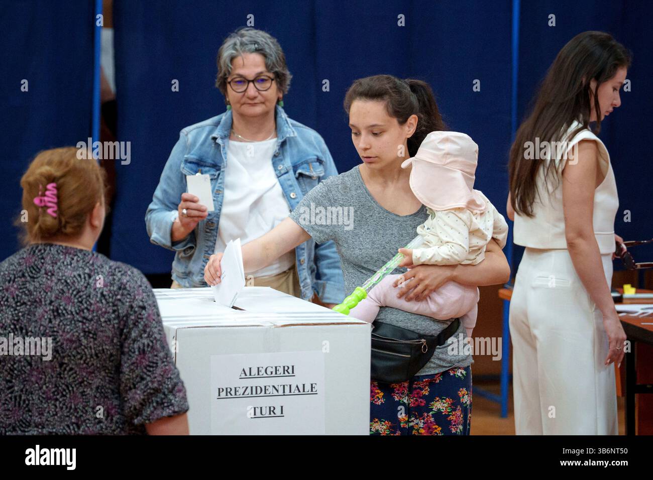 A woman holds a baby as she casts her vote in the first round of the ...