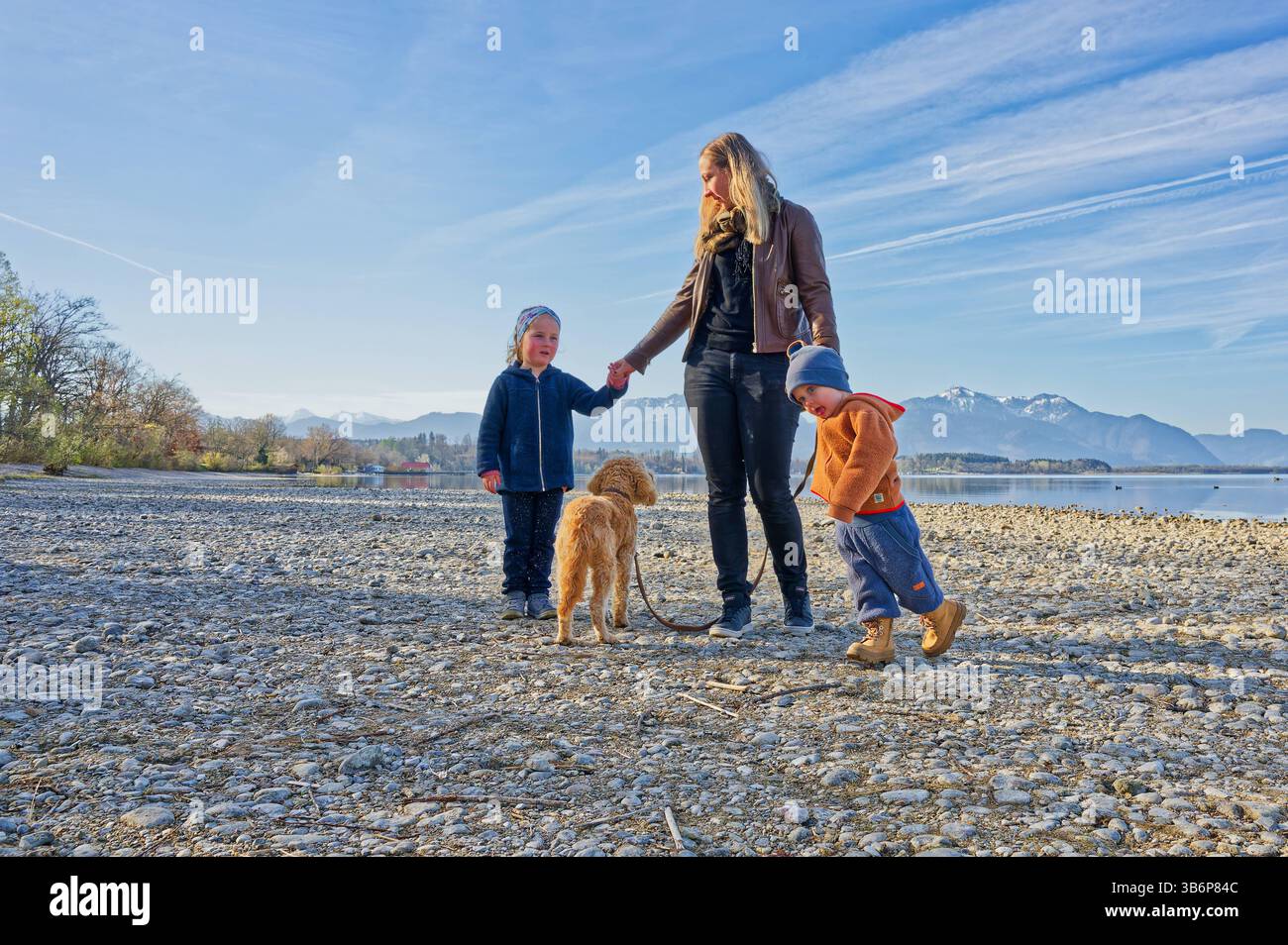 Hand in Hand. Die Mutter mit Tochter, Sohn und jungem Hund am ...