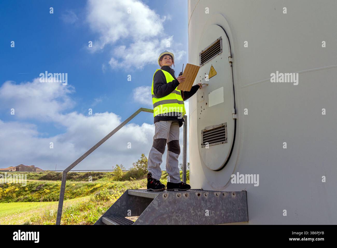 Female engineer inspecting wind turbine for renewable energy generation ...