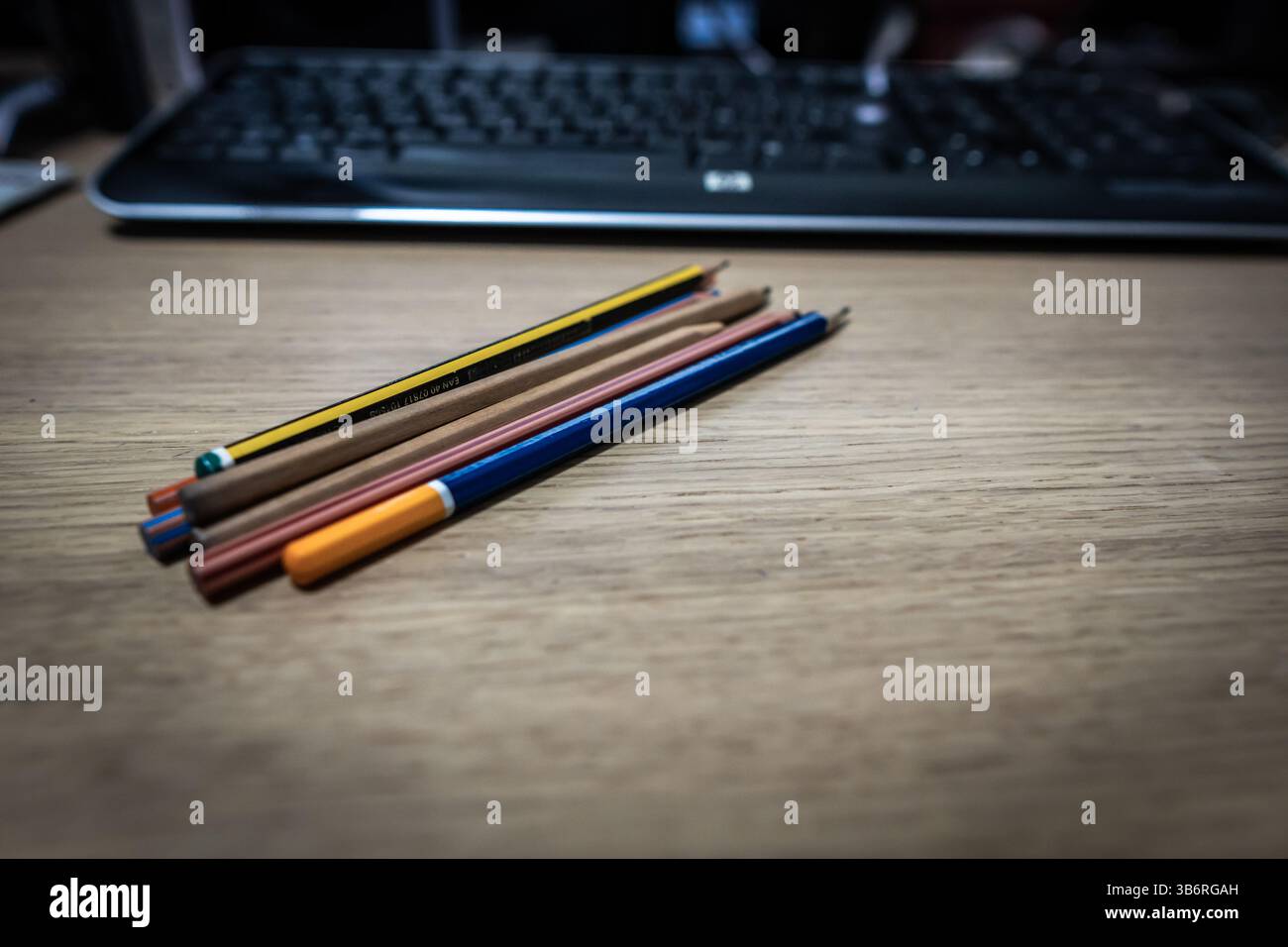 Colorful pencils lying on a desk with a computer keyboard in the ...