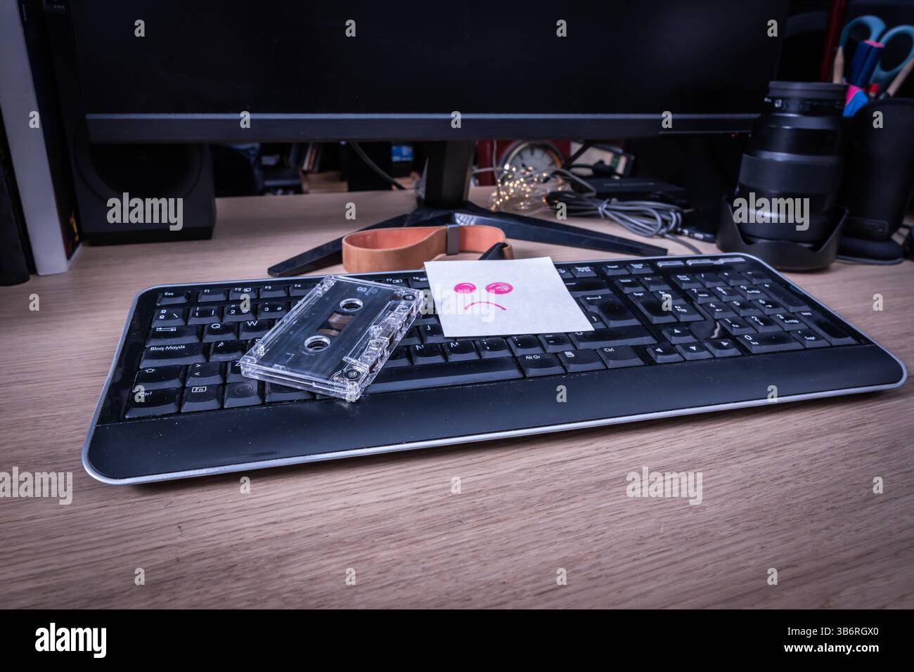 Transparent audio cassette and sad face emoji resting on computer ...