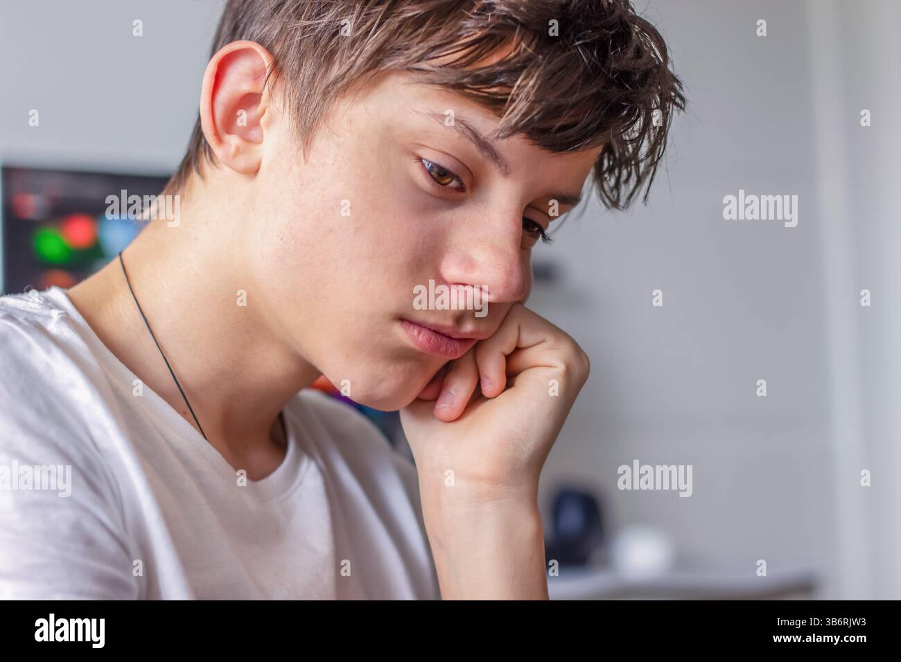 Portrait of a sad tired teenager, the guy supporting his face with his ...