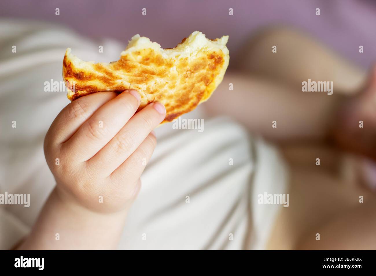 A piece of bitten pancake in a child's hands, a child eats pancakes ...