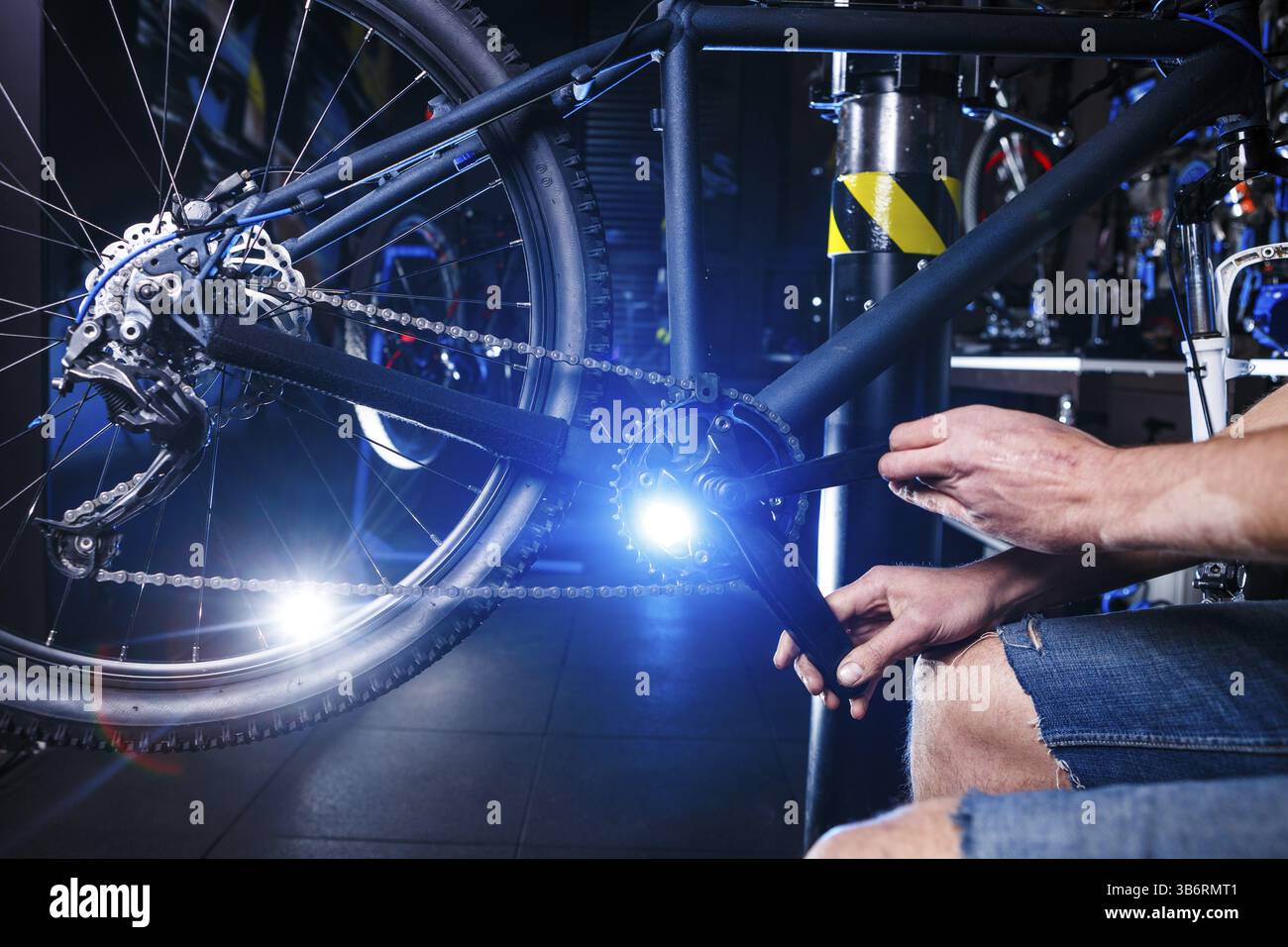A close-up of a male bicycle mechanic's hand in the workshop uses a ...