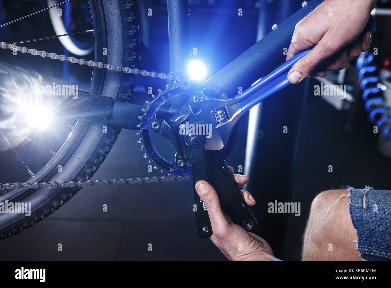 A close-up of a male bicycle mechanic's hand in the workshop uses a ...