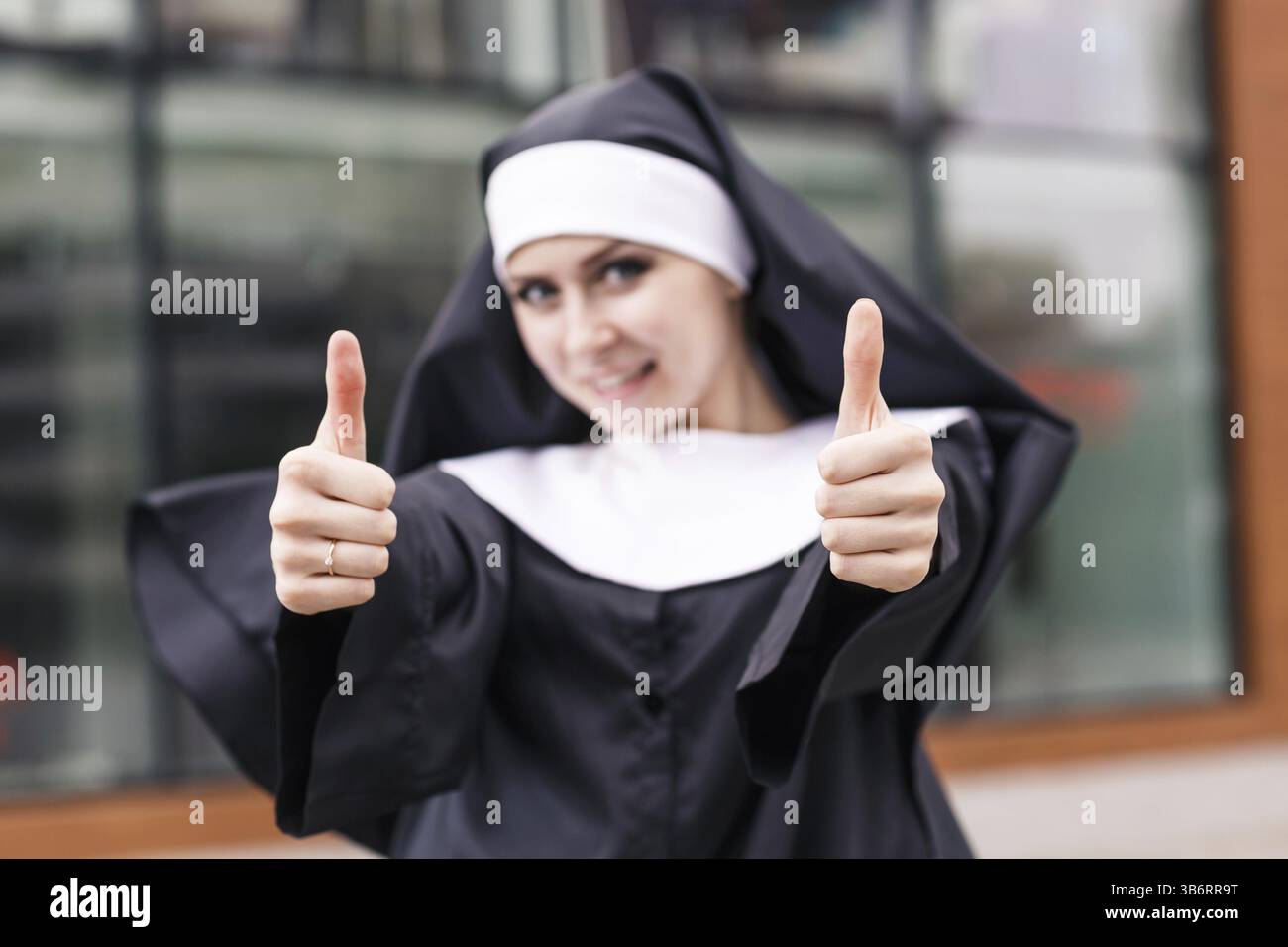 Young beautiful nun giving thumbs up outdoors Stock Photo - Alamy
