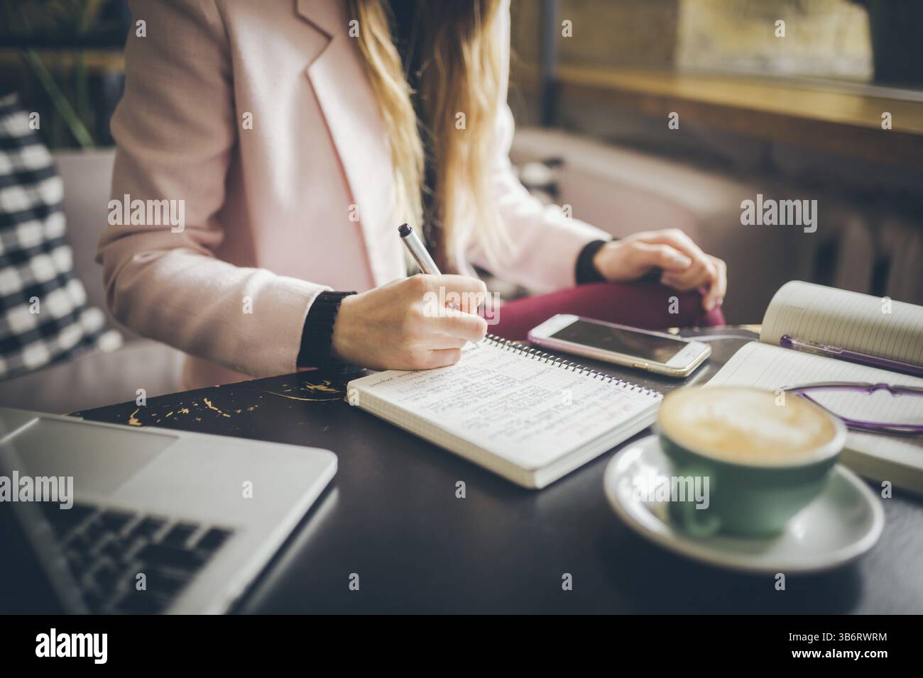 Close up caucasian woman hand on wooden table inside cafe makes notes ...