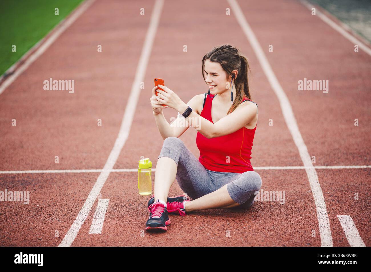Beautiful fitness girl uses smartphone at stadium after workout. Sports ...