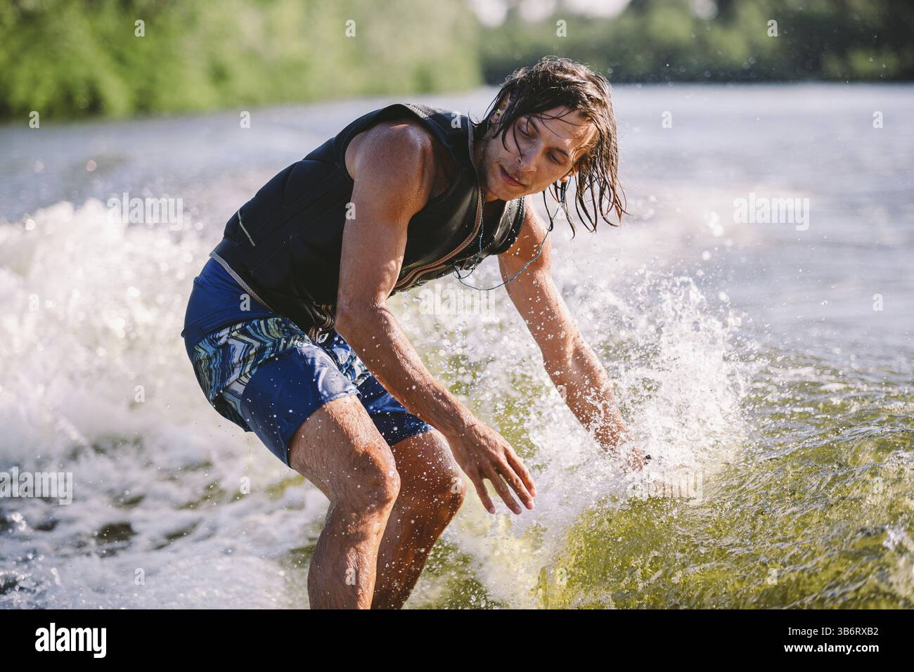 Active wakesurfer jumping on wake board down the river waves. Surfer on wave. Male athlete ...