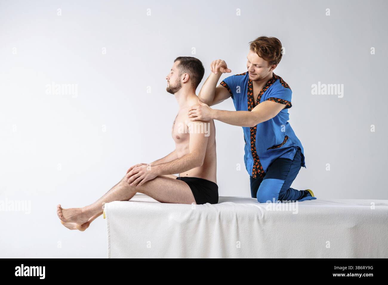 Theme massage and body care. A handsome Caucasian male doctor in blue ...