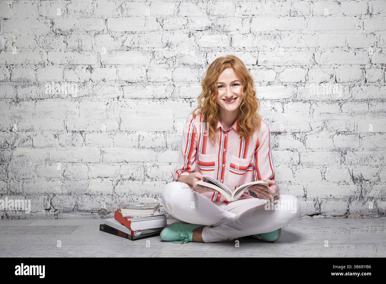 Happy student girl with red hair and freckles prepares homework ...