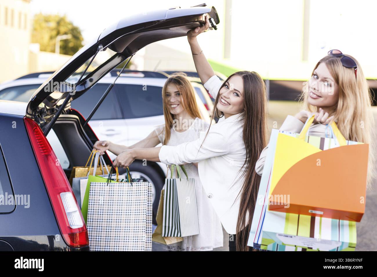 Group of girls after shopping loading a shopping bags in a car trunk Stock Photo - Alamy