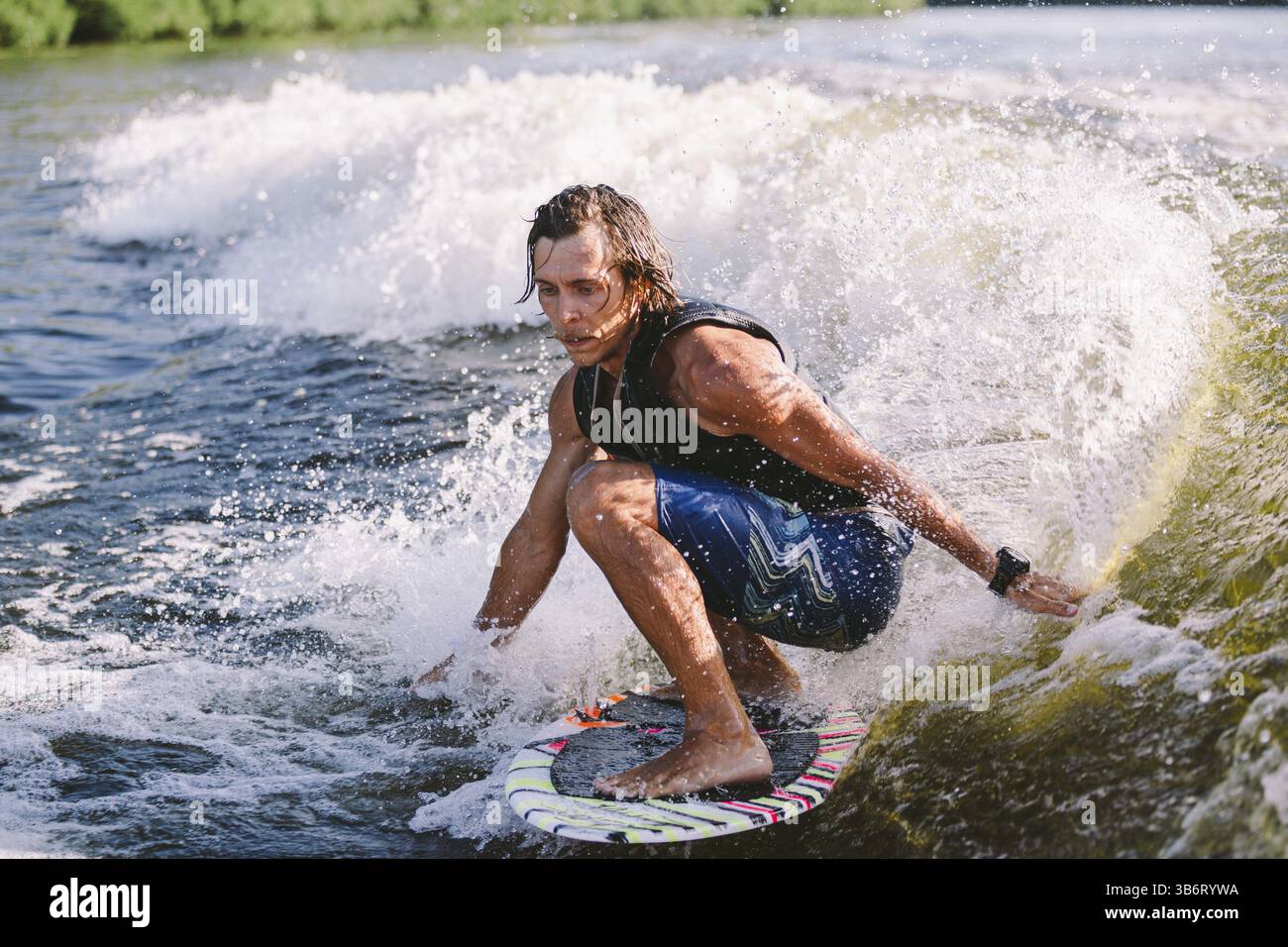 Beautiful long haired blond wakesurf in vest on board along waves of ...