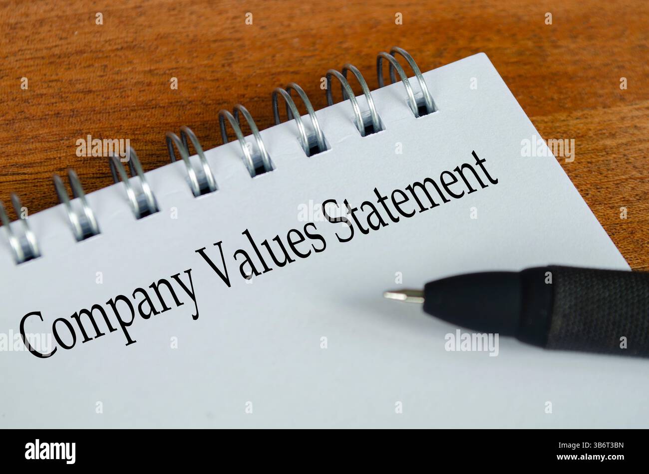 Company Values Statement text on white notepad with wooden table ...