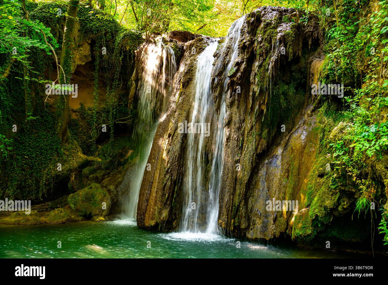 A breathtaking waterfall flows gracefully into a tranquil pool ...
