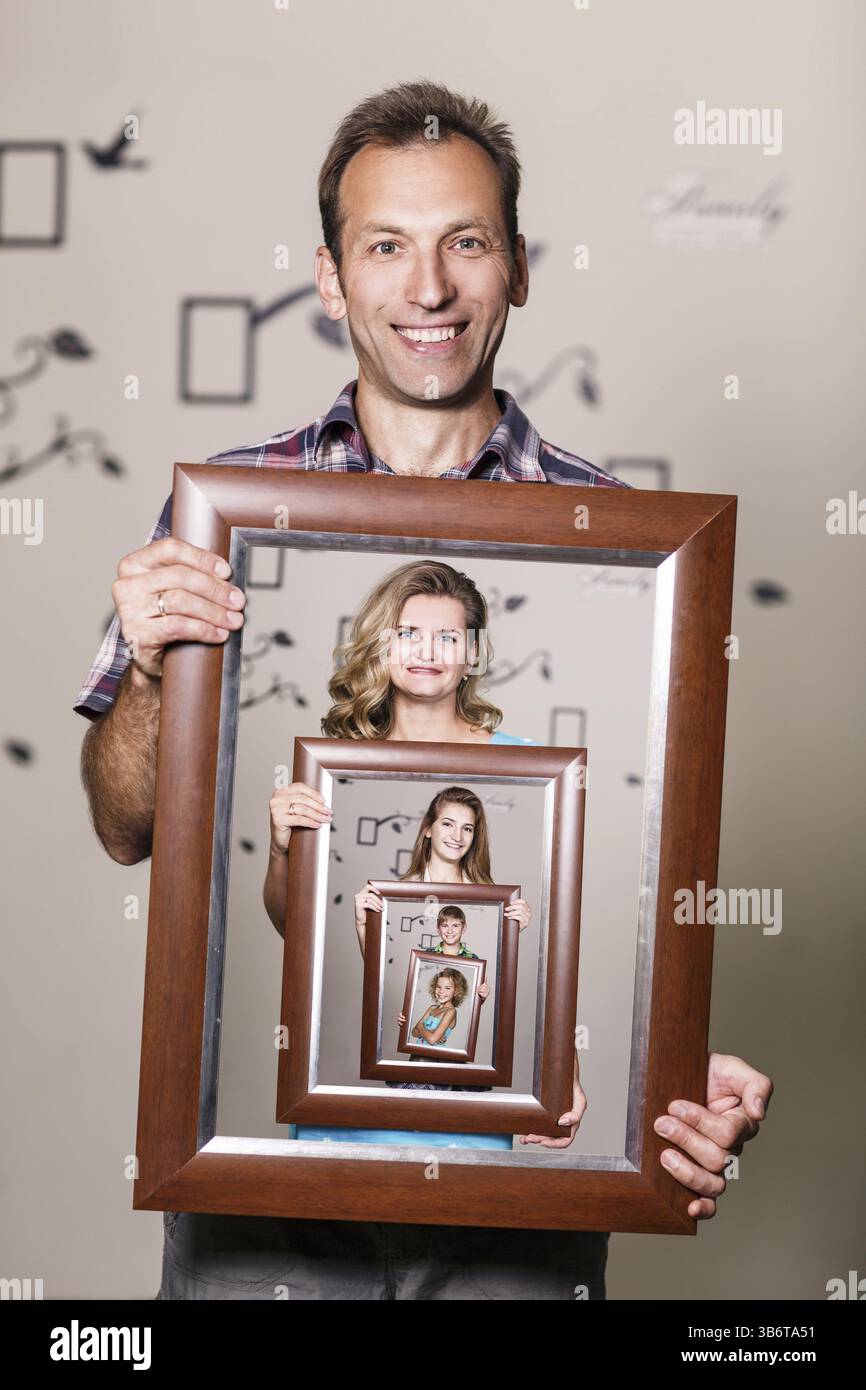 Happy father holding portrait with his family each is located inside ...