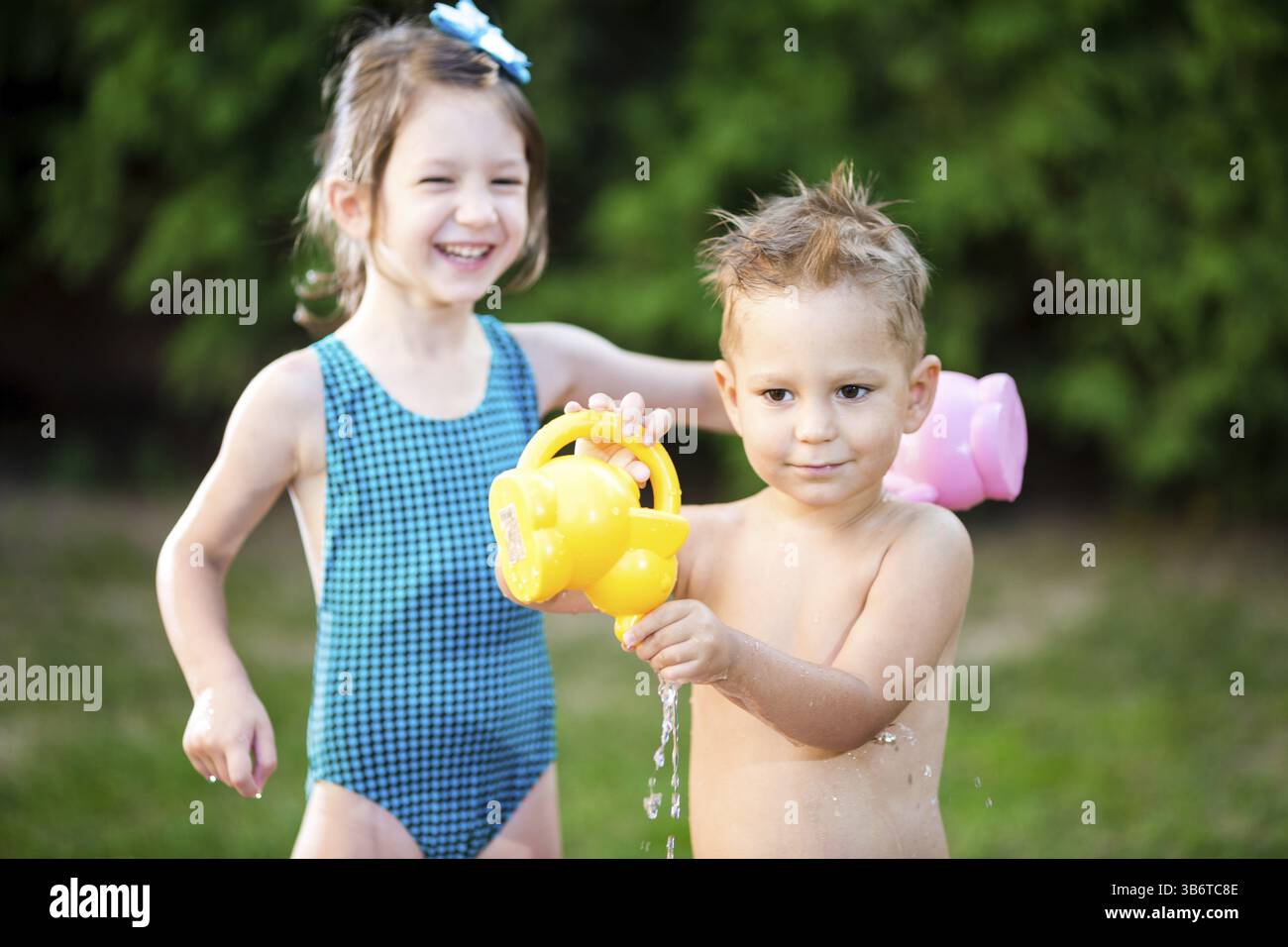 Childhood summer games with water pool. Caucasian brother and sister ...